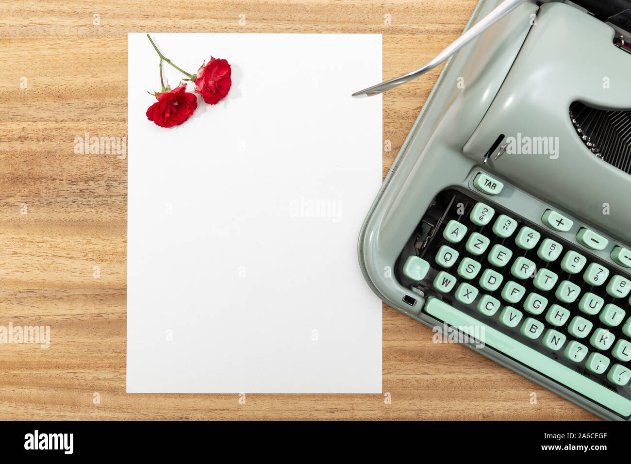 Love letter. Desk with blank paper, retro typewriter and red roses and ...