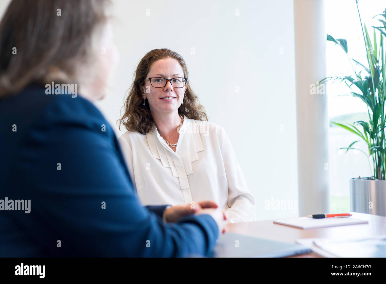 Women sit around a meeting table holding a productive meeting Stock ...