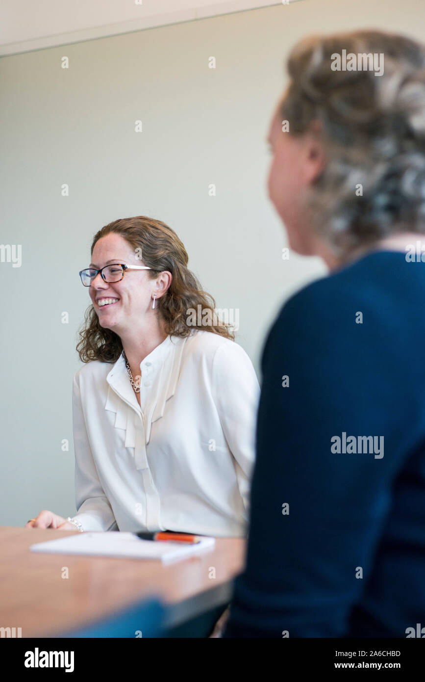 Women sit around a meeting table holding a productive meeting Stock ...