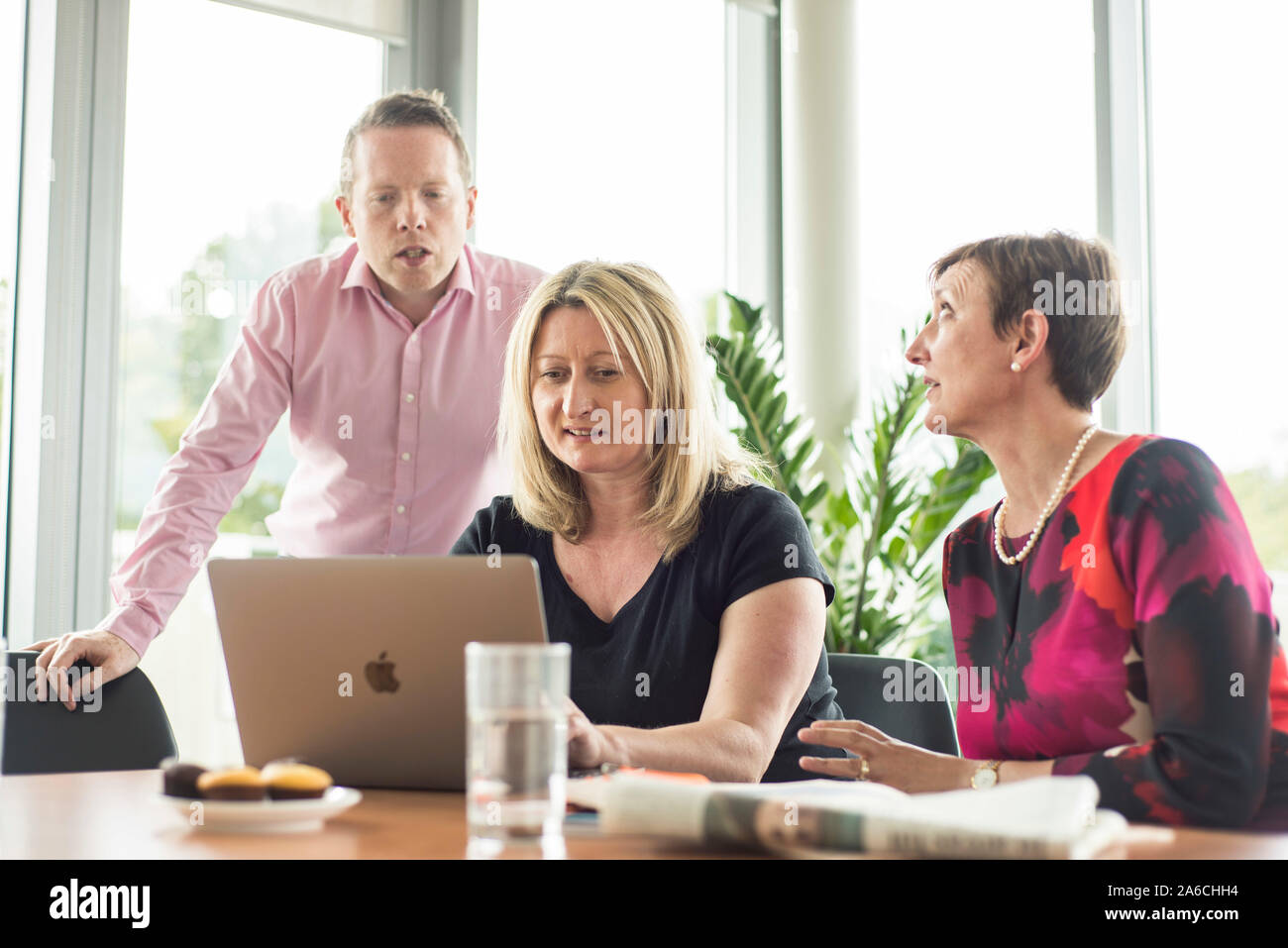 two women and a man work on a lap top computer together Stock Photo - Alamy