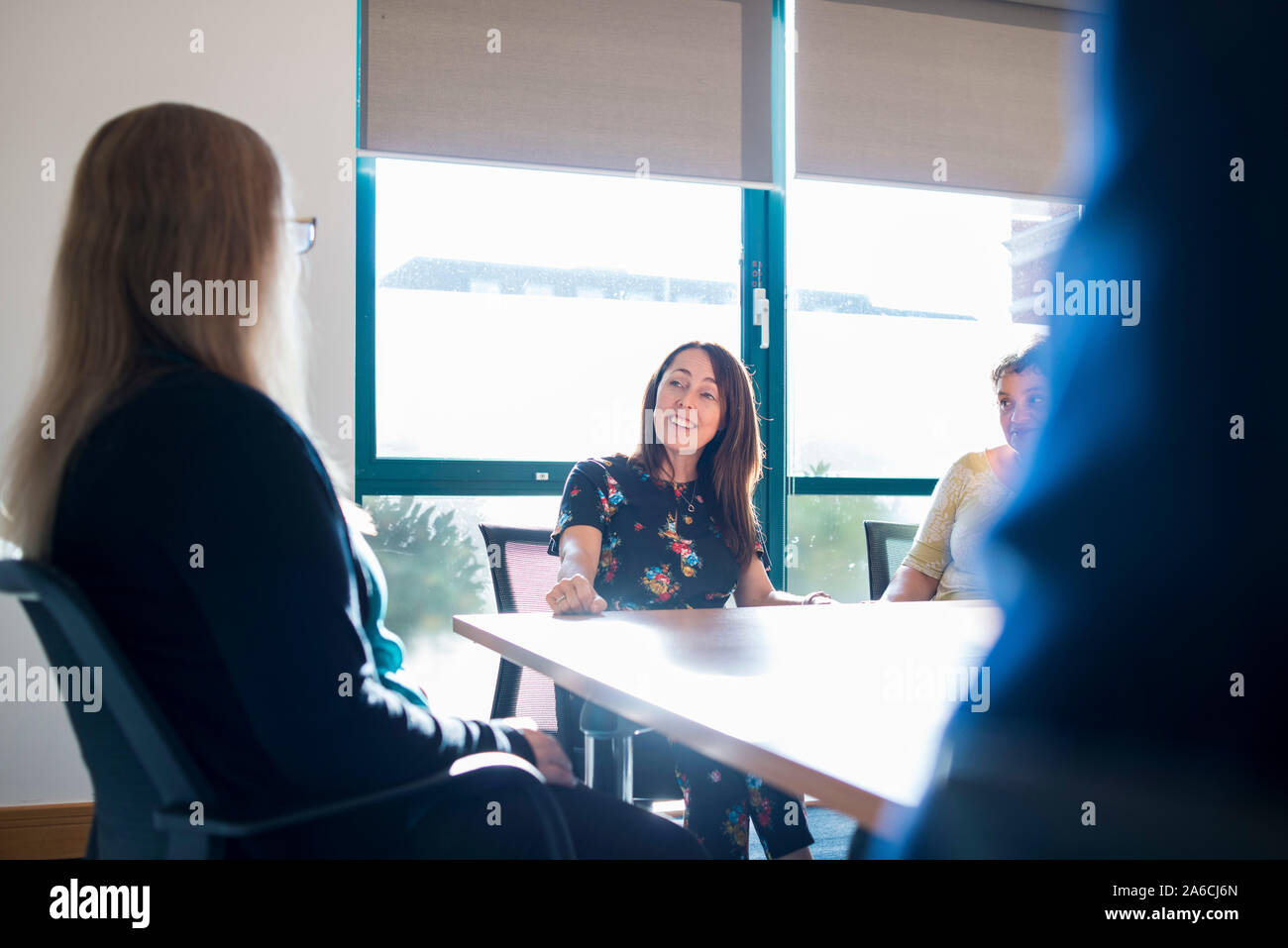 Women sit around a meeting table holding a productive meeting Stock ...