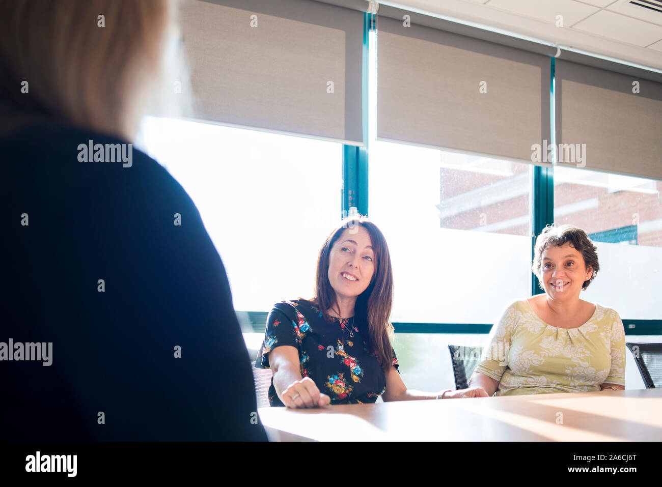 Women sit around a meeting table holding a productive meeting Stock ...