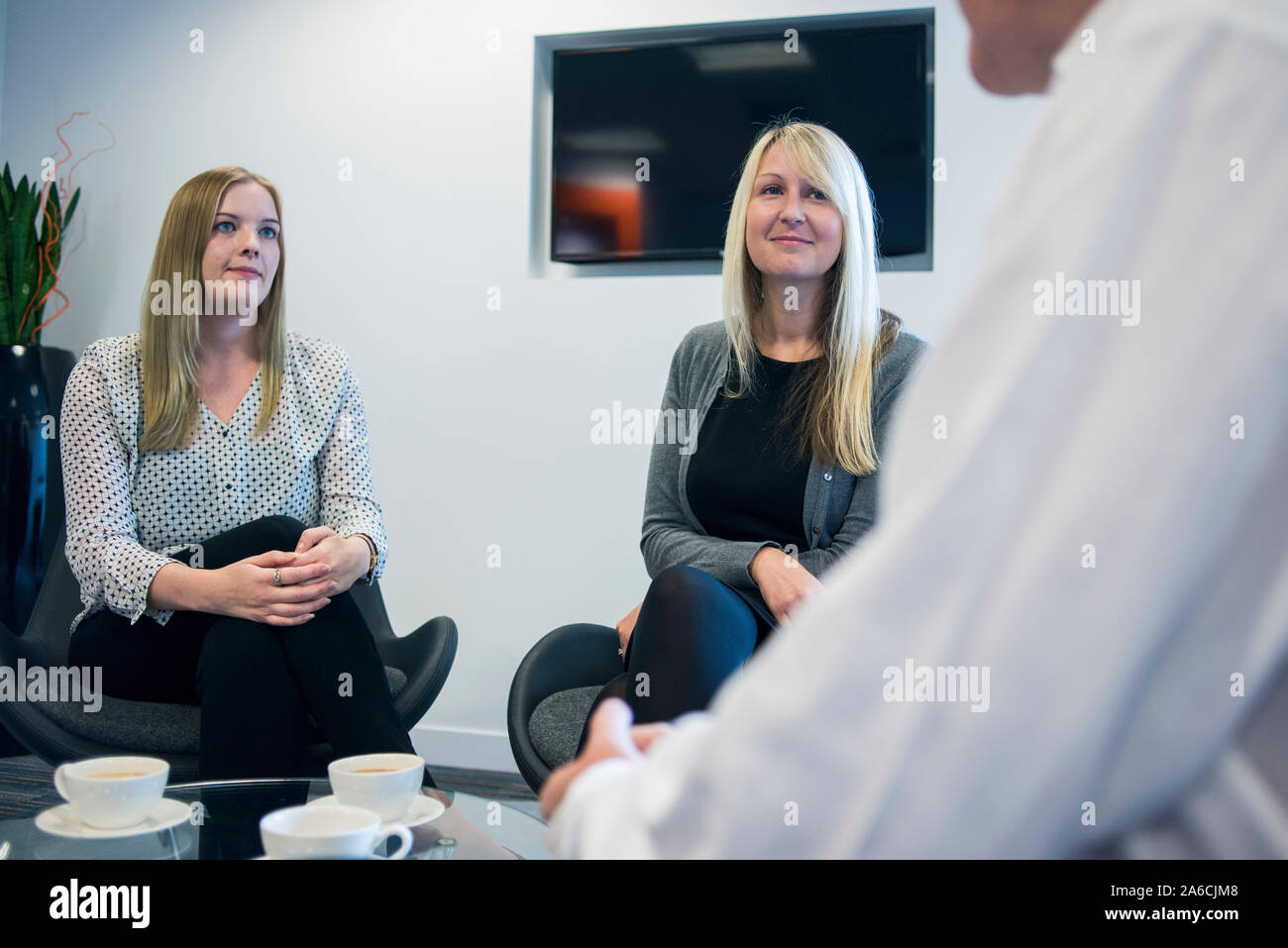 Two women talk with their manager in an informal meeting with coffee ...
