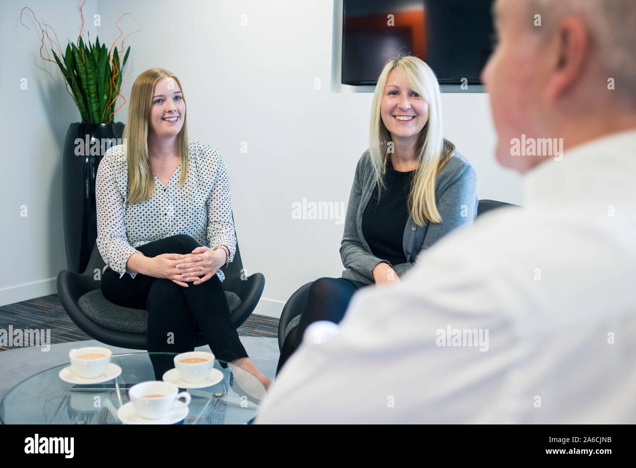 Two women talk with their manager in an informal meeting with coffee ...