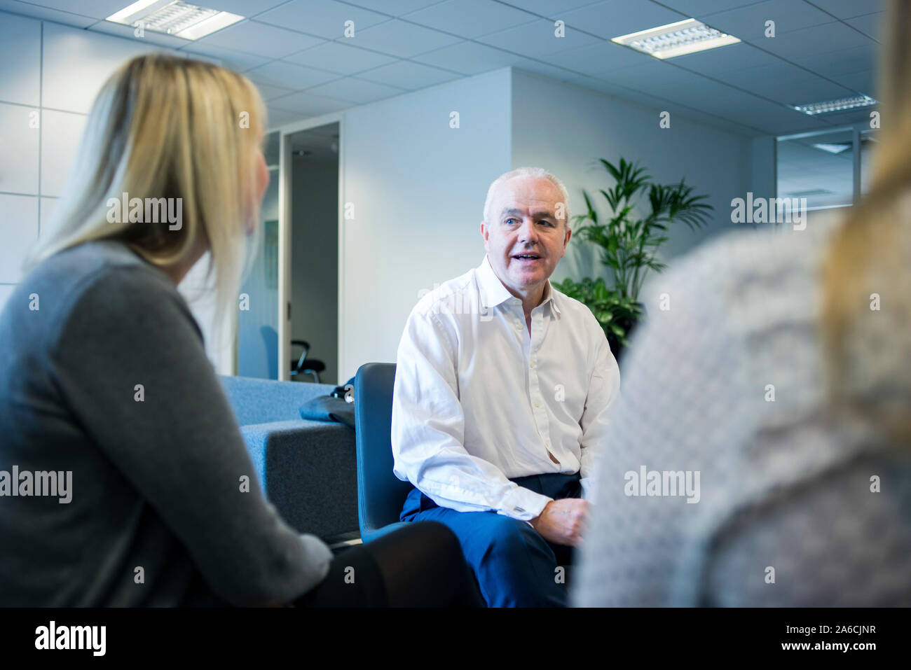 Two women talk with their manager in an informal meeting with coffee ...