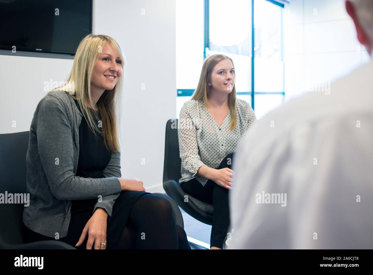 Two women talk with their manager in an informal meeting with coffee ...