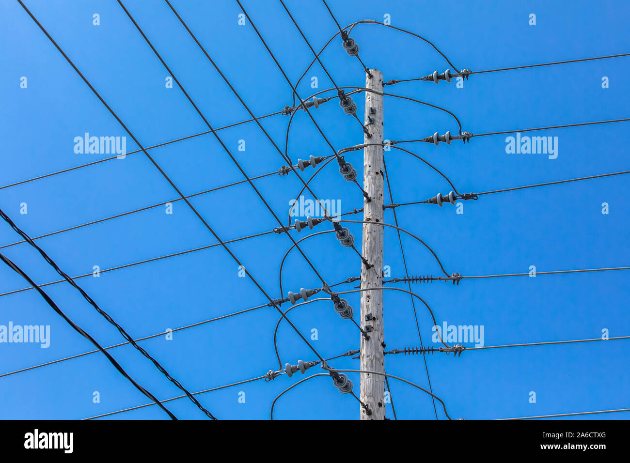 A low angle view of a tall wooden utility pole supporting overhead ...