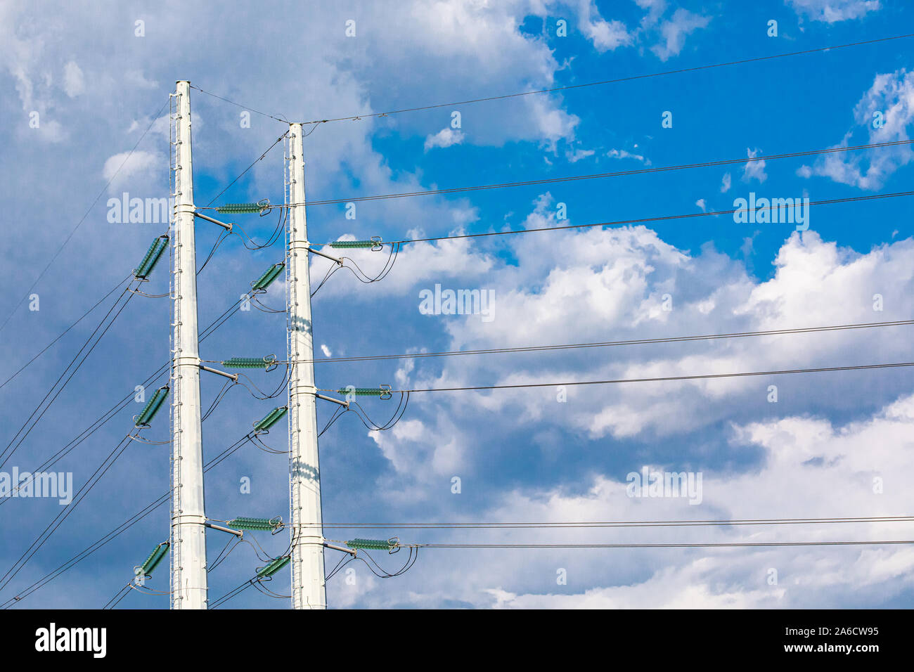Two utility poles are viewed from below, supporting overhead electric ...
