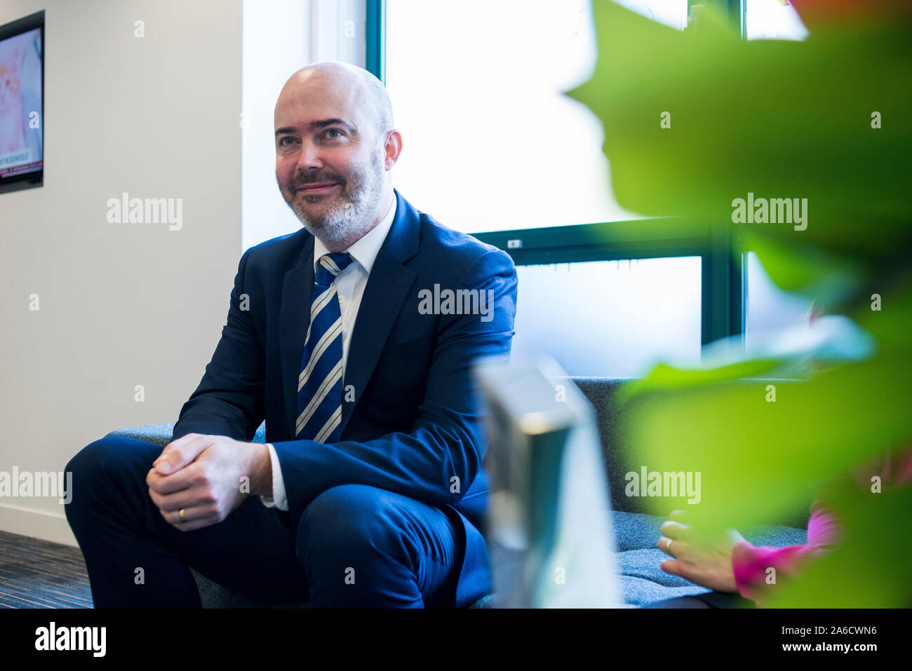A male office worker sits in an informal setting having a relaxed ...