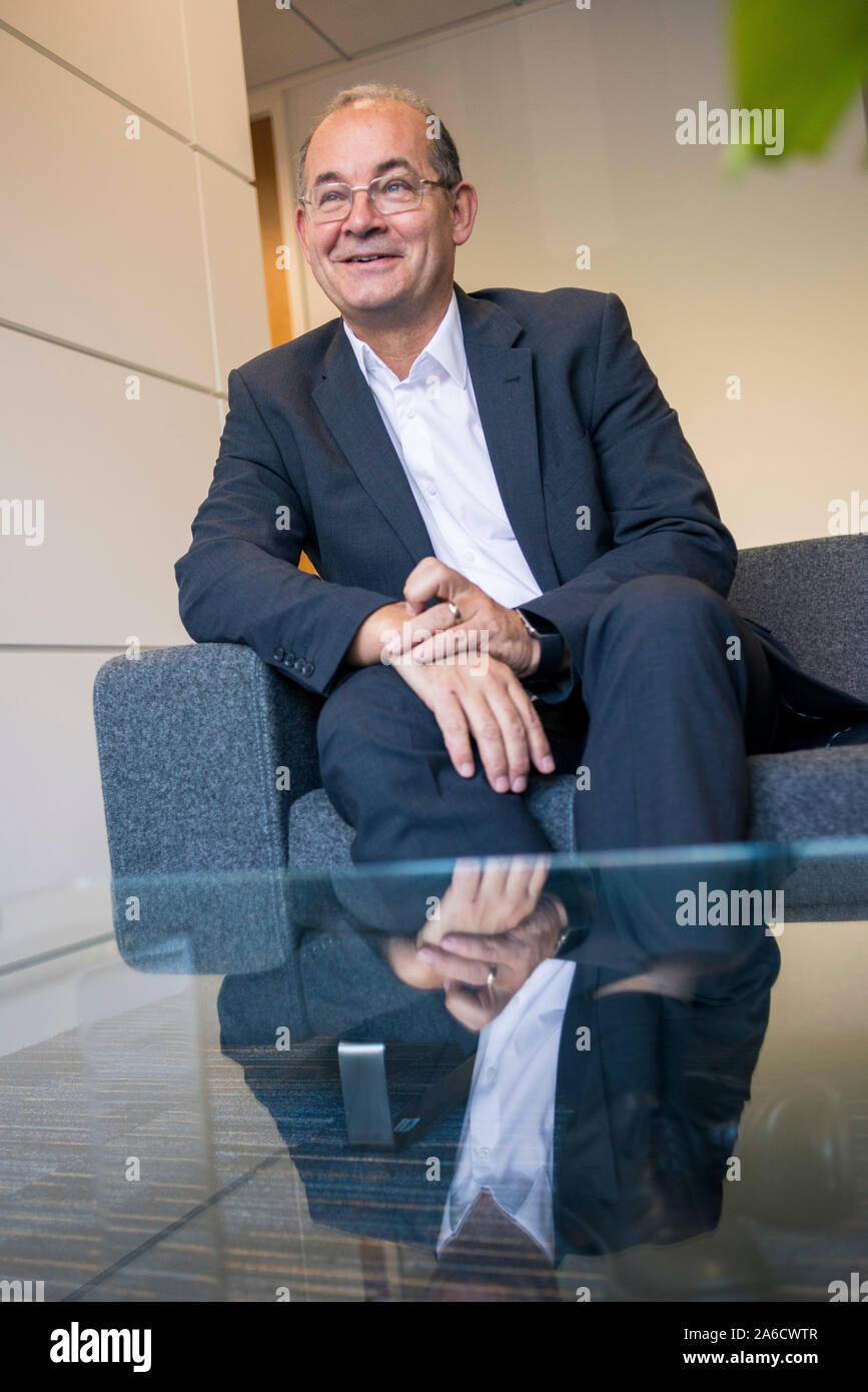 A male office worker sits in an informal setting having a relaxed ...