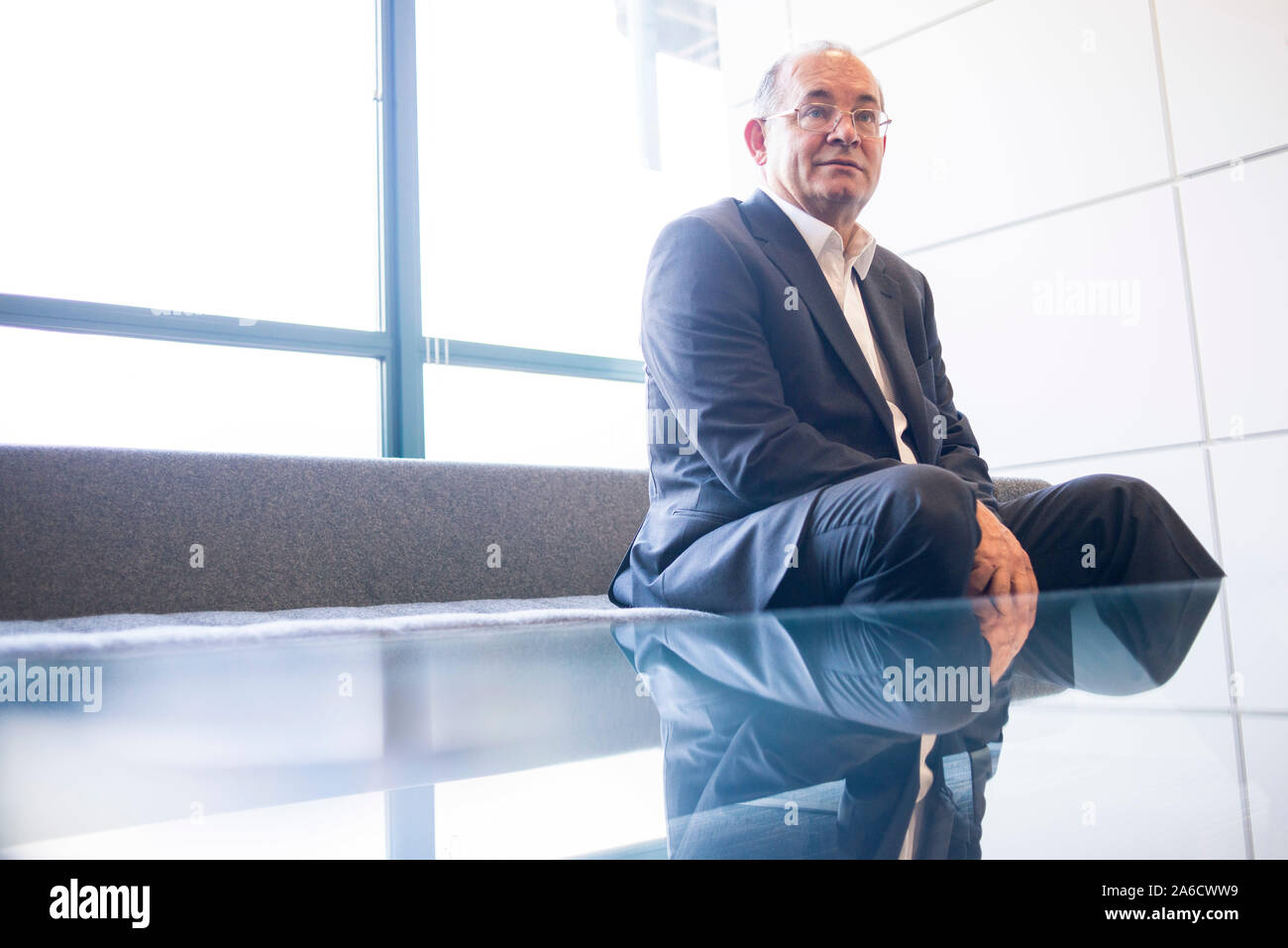 A male office worker sits in an informal setting having a relaxed ...