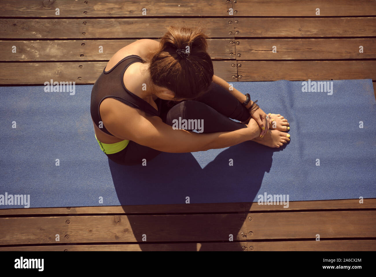 Top view of a woman in black top and leggings practicing yoga ...