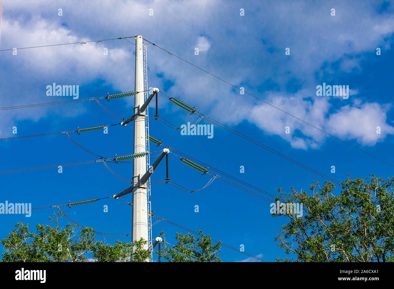 A low angle view of a tall white utility pole supporting overhead ...