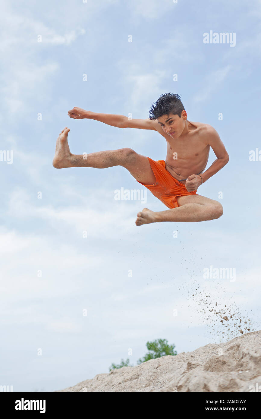 A teenage boy is jumping jauntily at a beach Stock Photo - Alamy