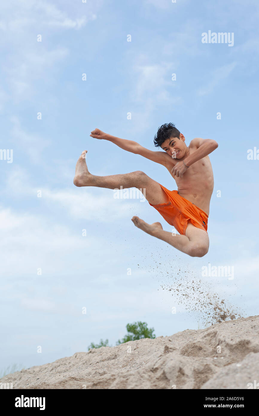 A teenage boy is jumping jauntily at a beach Stock Photo - Alamy