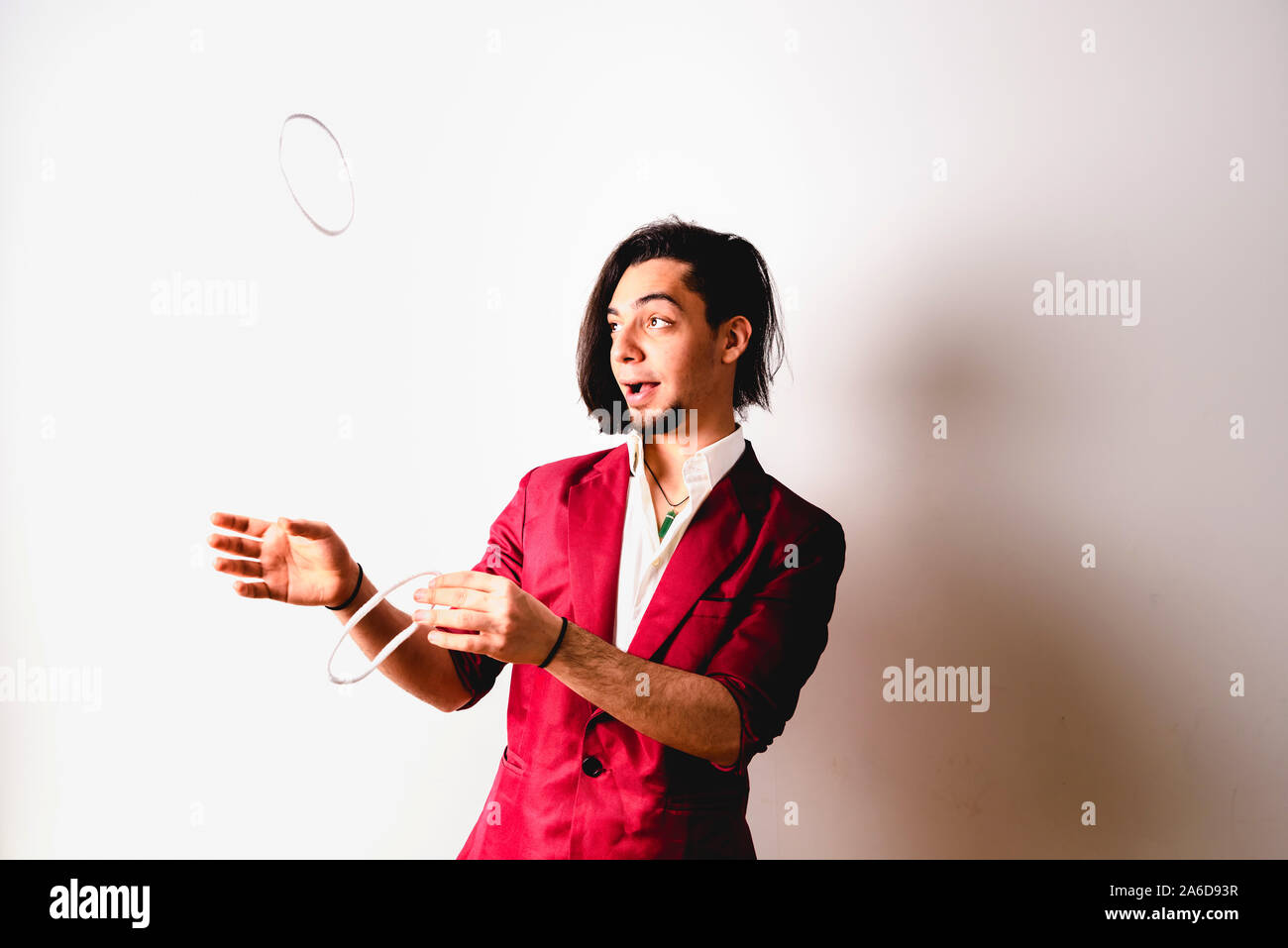 Portrait of young magician handling ropes and bandanas to do magic ...