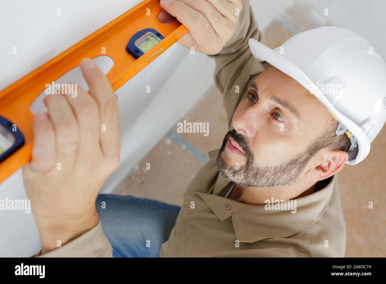 portrait of builder man leveling wall Stock Photo - Alamy