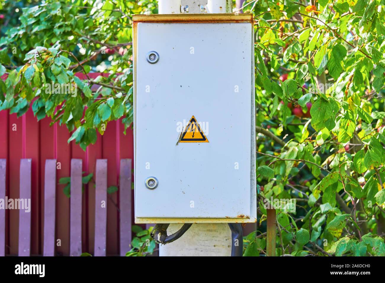 Locked rusty grey electric panel with hazard sign on the grey concrete ...