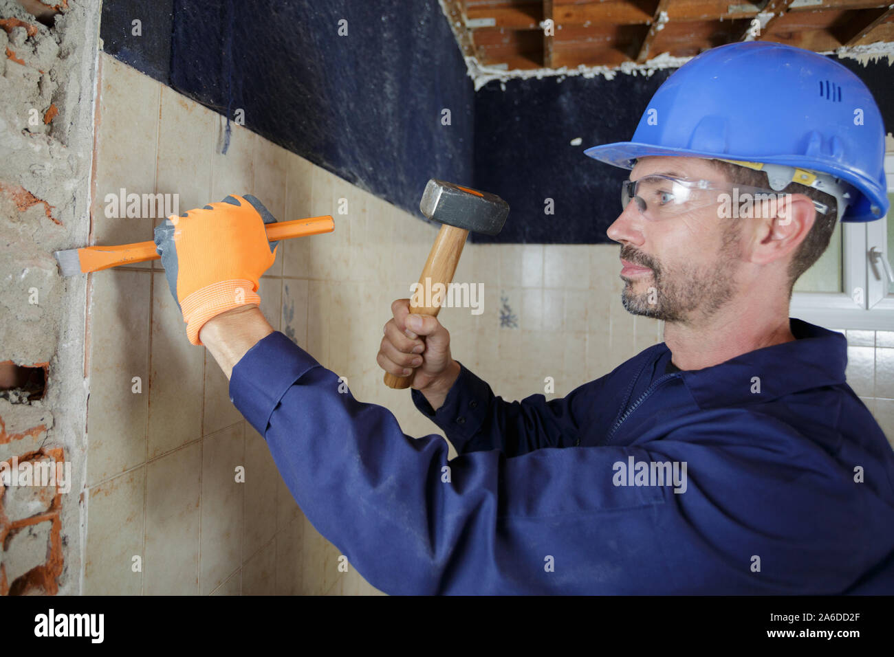 male builder using hammer chisel on interior wall Stock Photo - Alamy