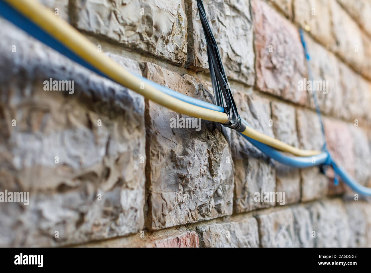 Hanging old network electrical cables on stone wall outdoors Stock ...