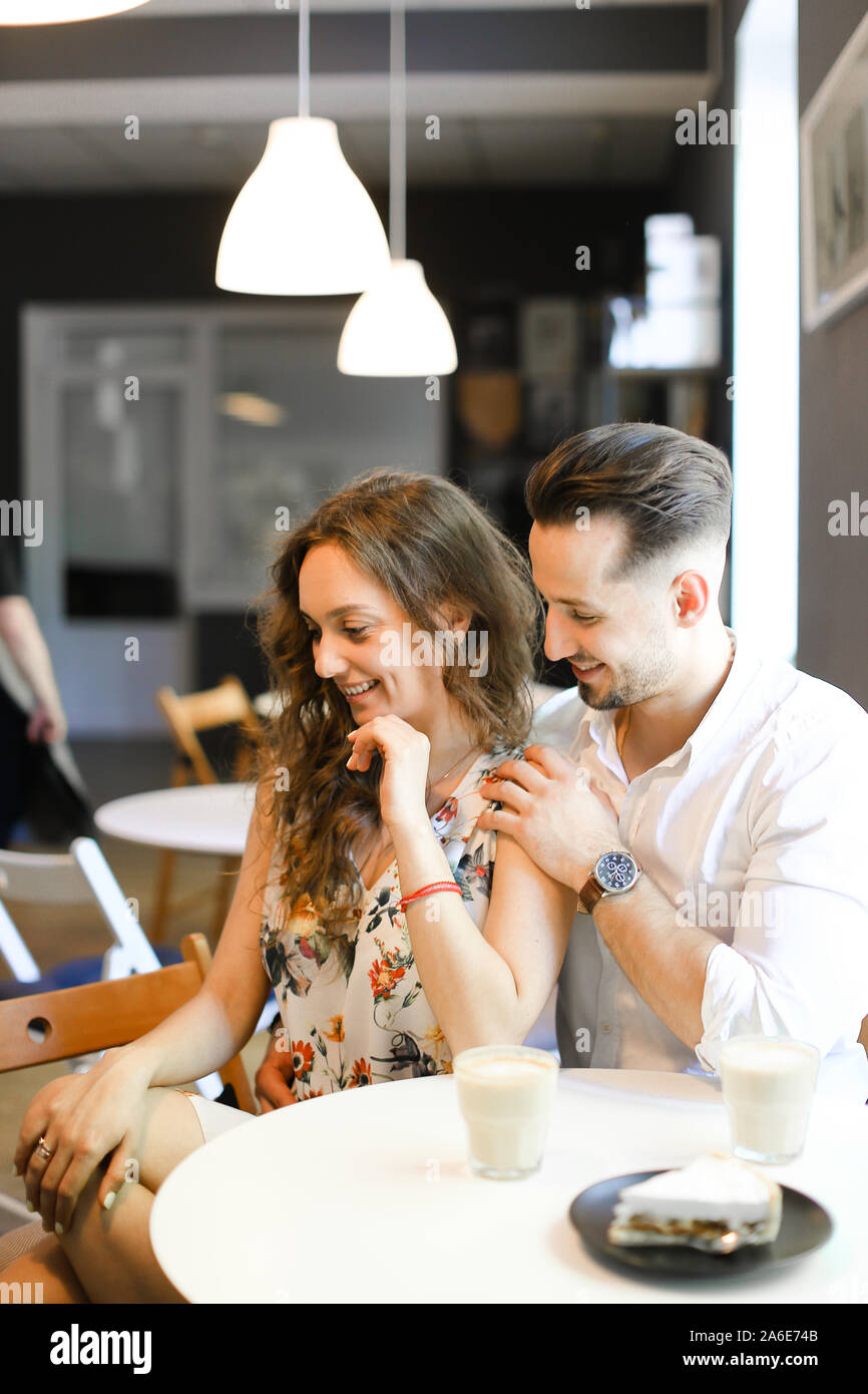 Young handsome gentleman hugging girl at cafe, ,sitting near cups of ...