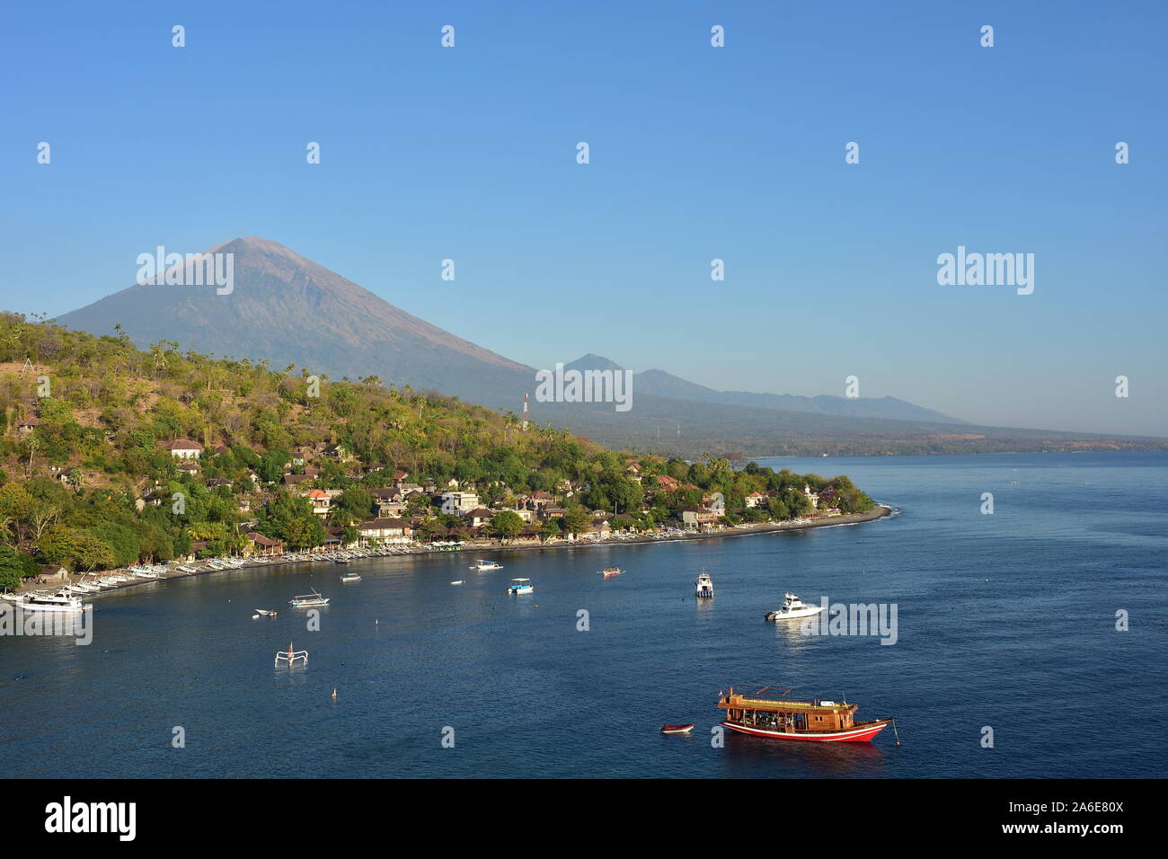 Calm bay with recreational boats on east coast of Bali with chain of ...