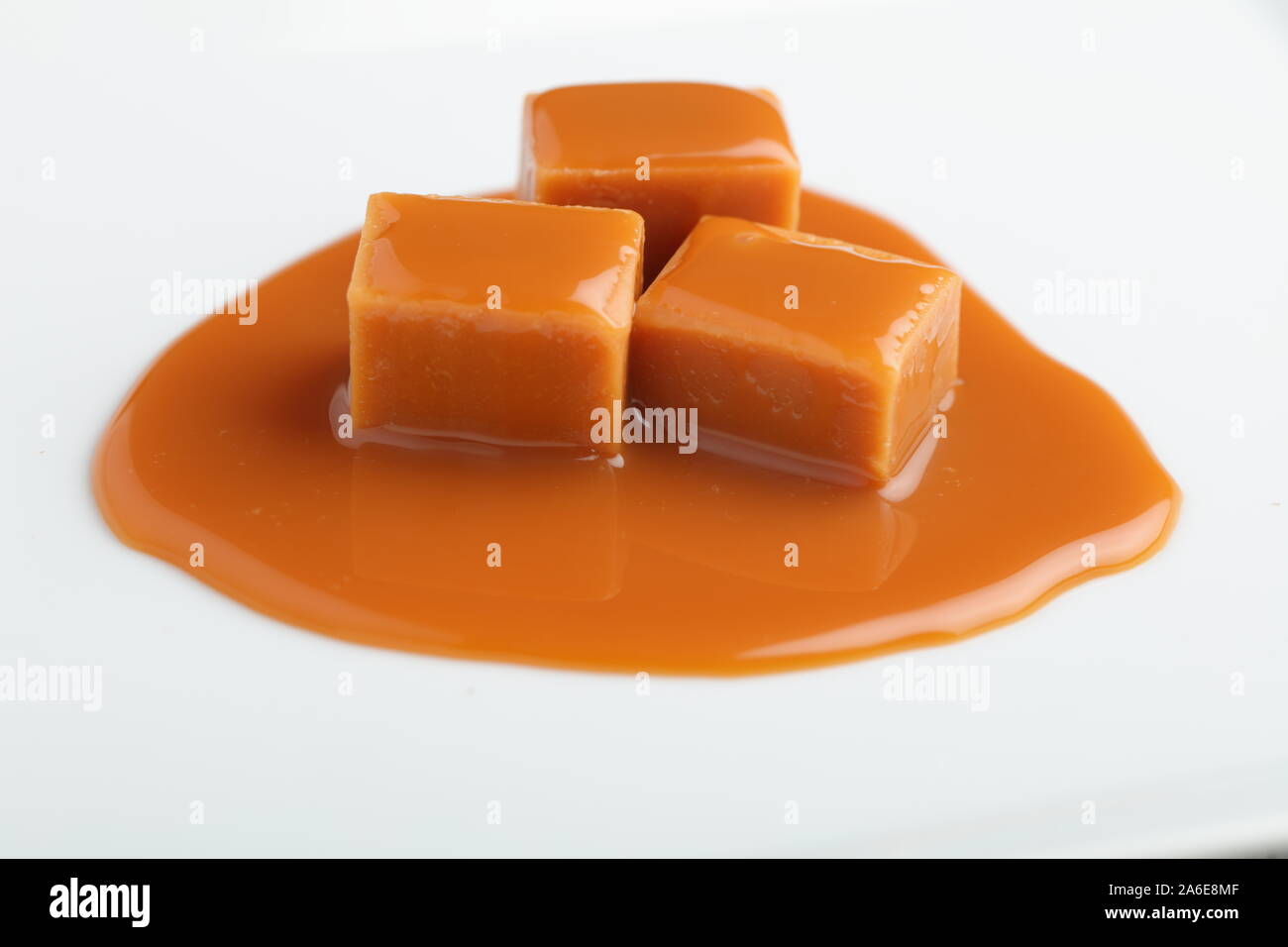 Three blocks of fudge under caramel sauce on white background Stock ...