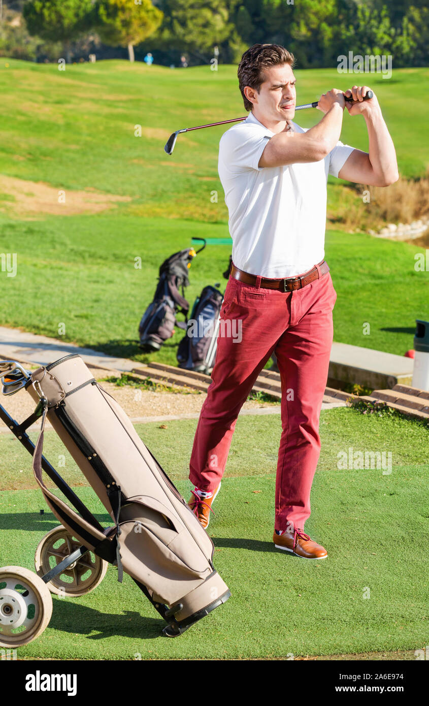 Glad positive male golf player made successful hit at golf course Stock ...