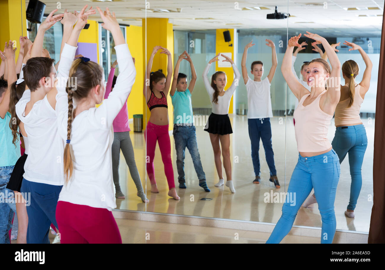 Positive dance teacher giving children dance class, showing movements ...