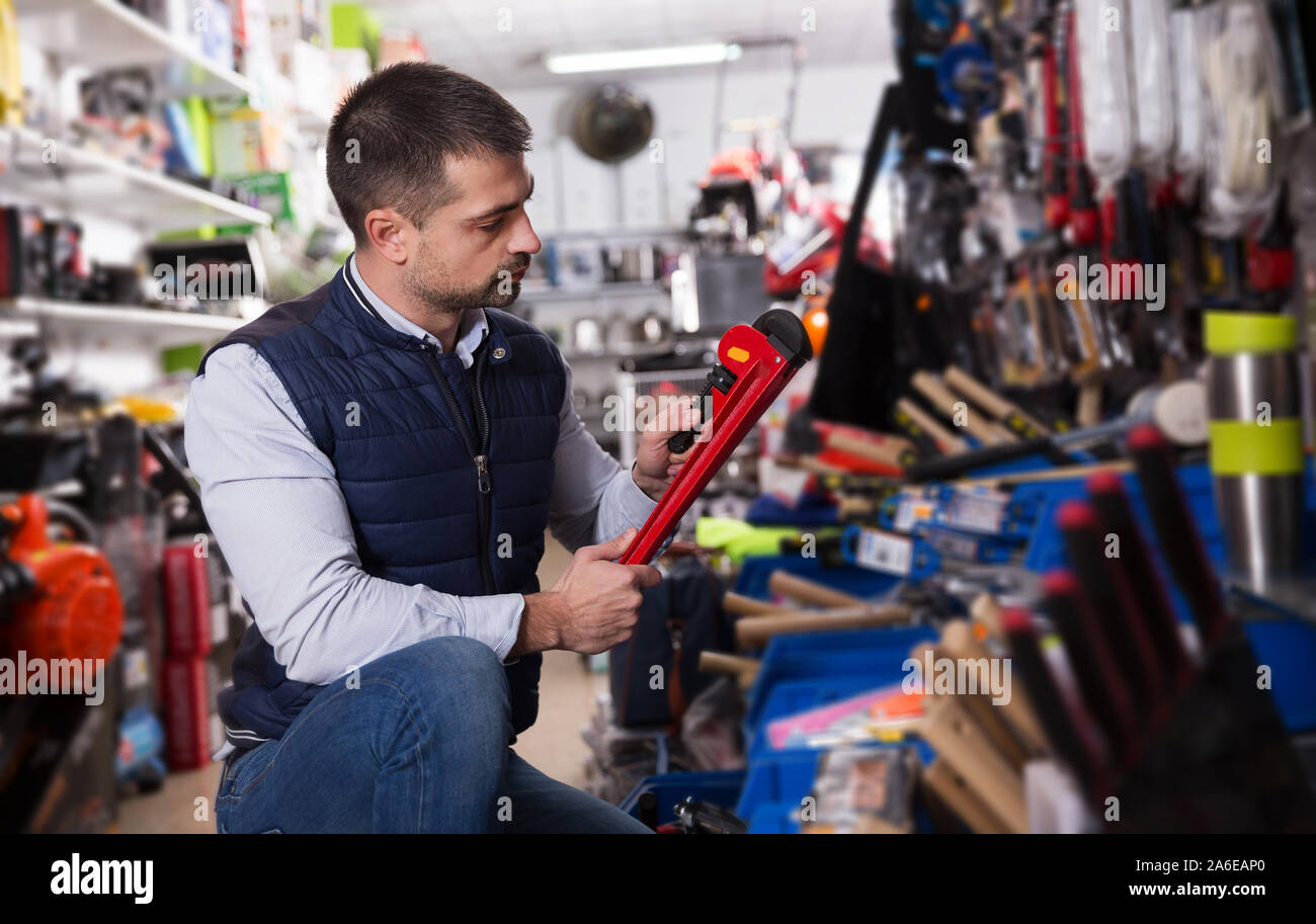 positive male is standing with new adjustable wrench in tools store ...