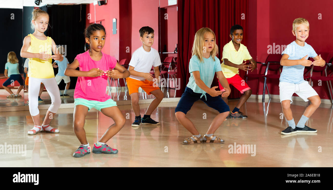 Fine children primary school age rehearsing movements of ballet dance ...