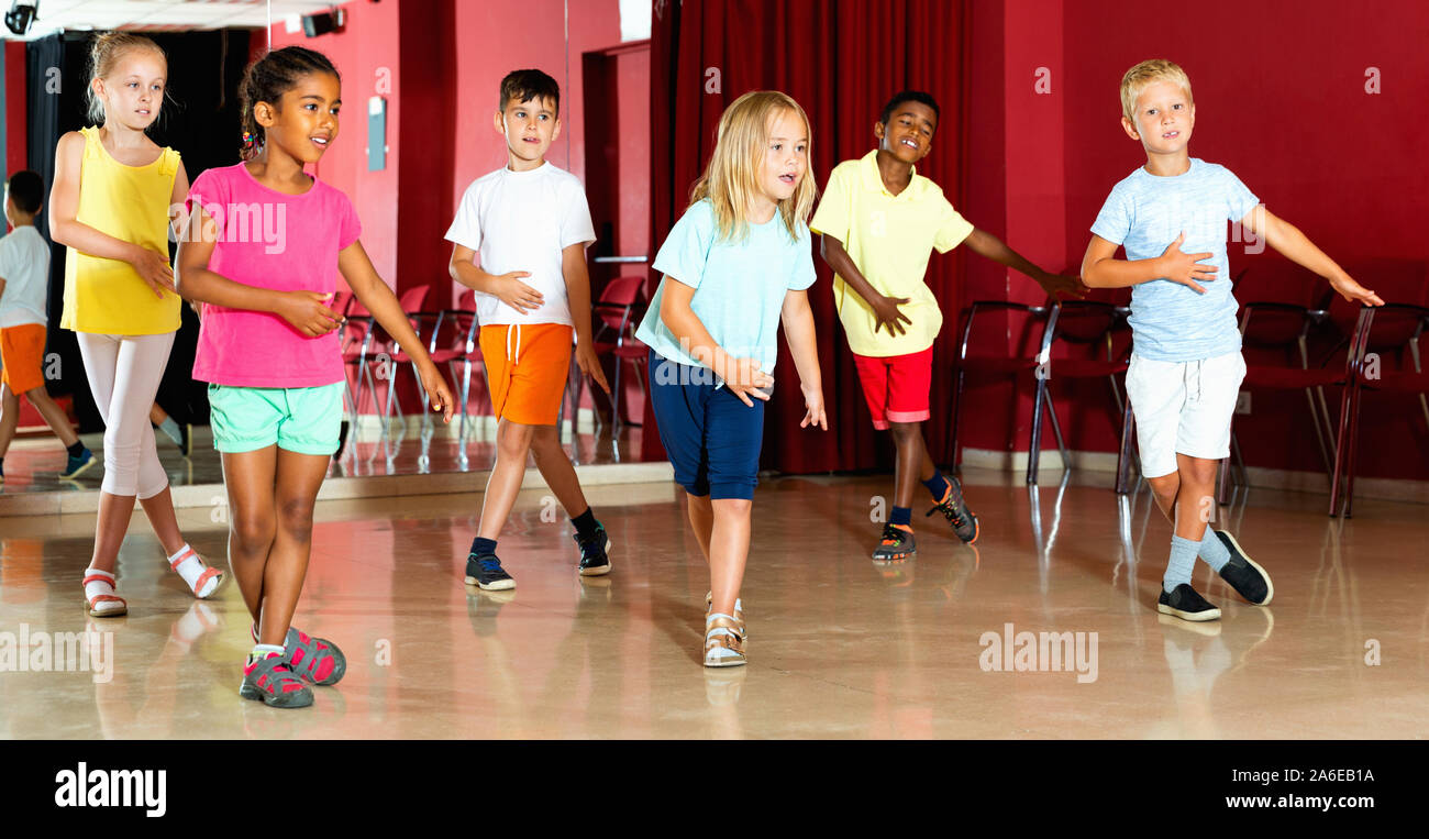 Positive happy cheerful children studying modern style dance in class ...