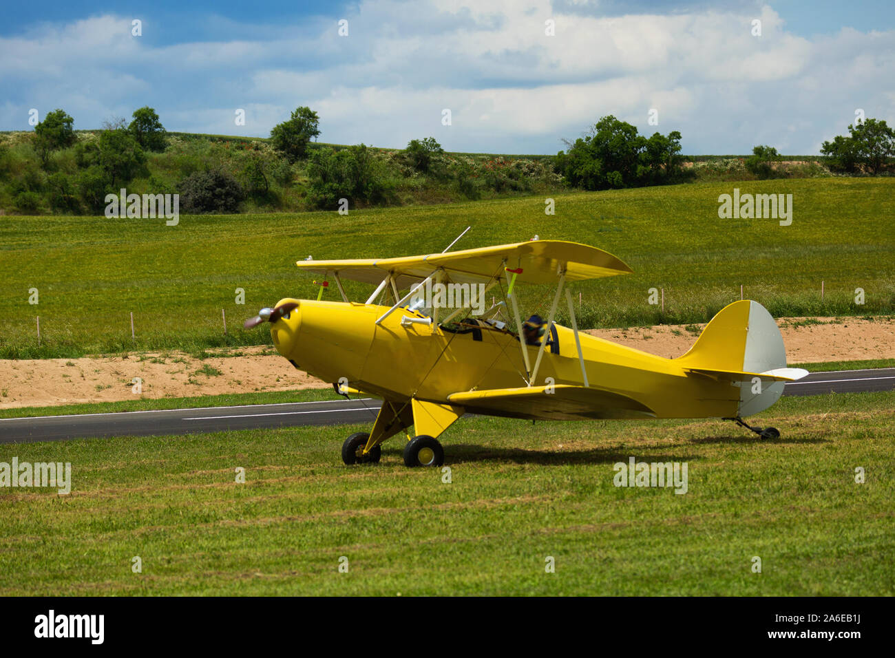 Yellow light biplane parked on green field on aerodrome Stock Photo - Alamy