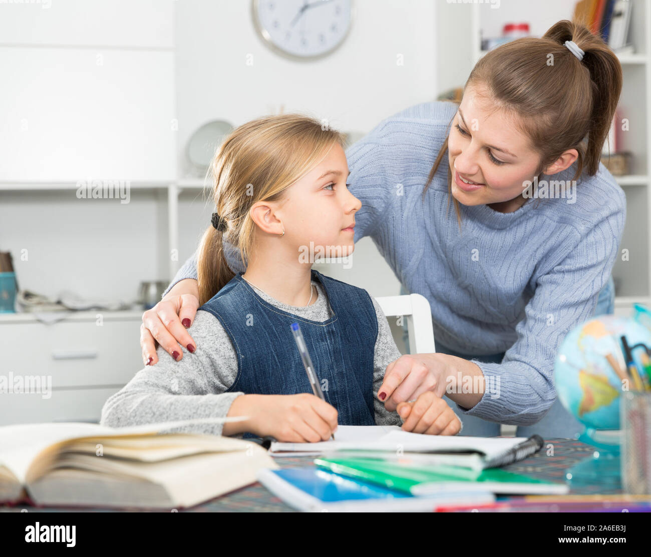 Mother checks school lessons daughters Stock Photo - Alamy