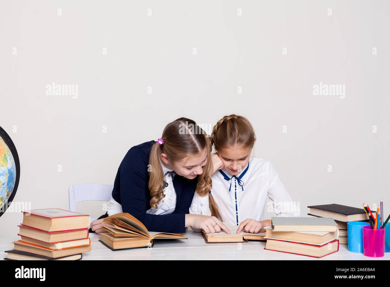 two schoolgirl girls with books at the school desk Stock Photo - Alamy