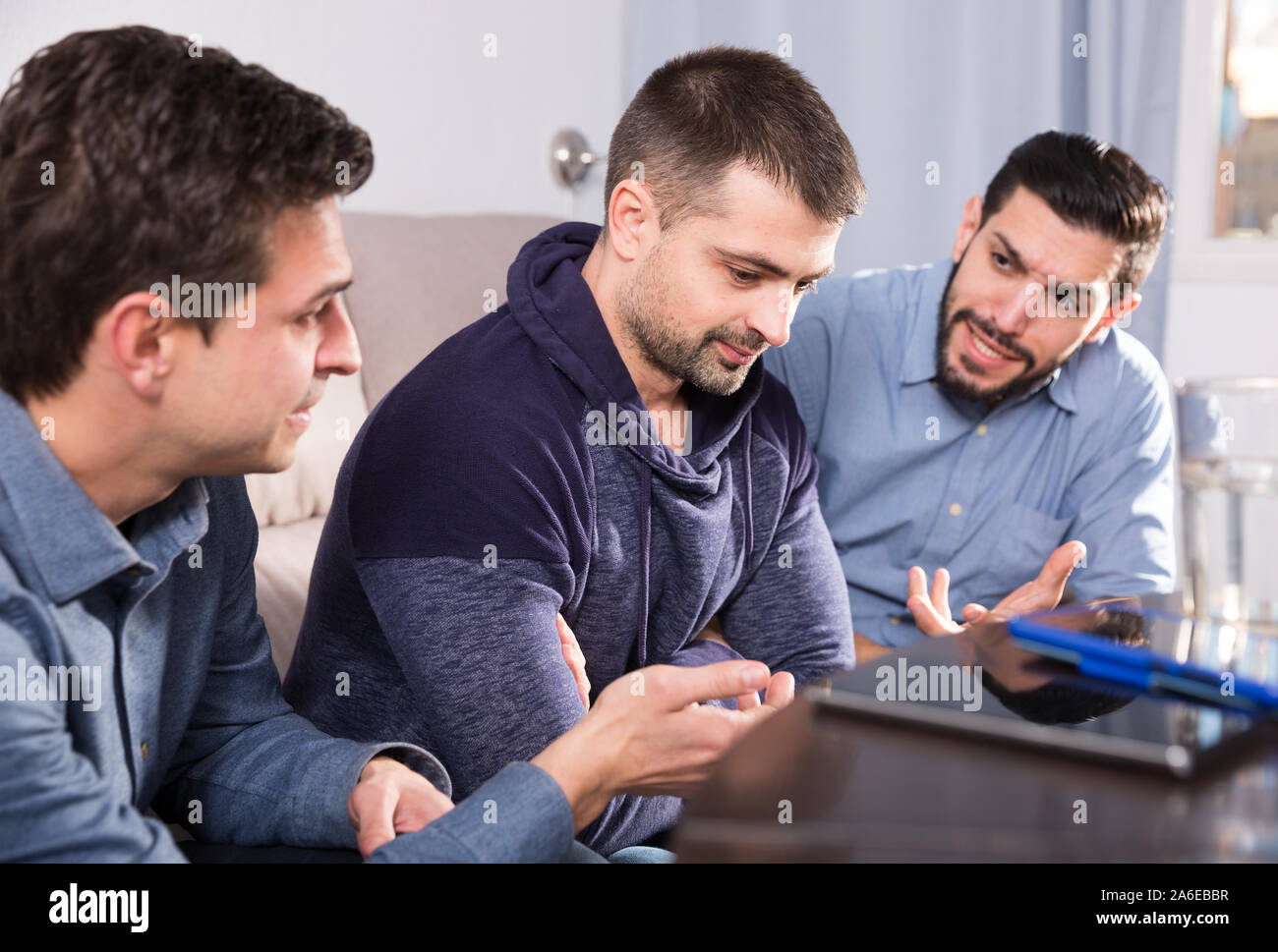 Two troubled men having serious talk with their friend at home Stock ...
