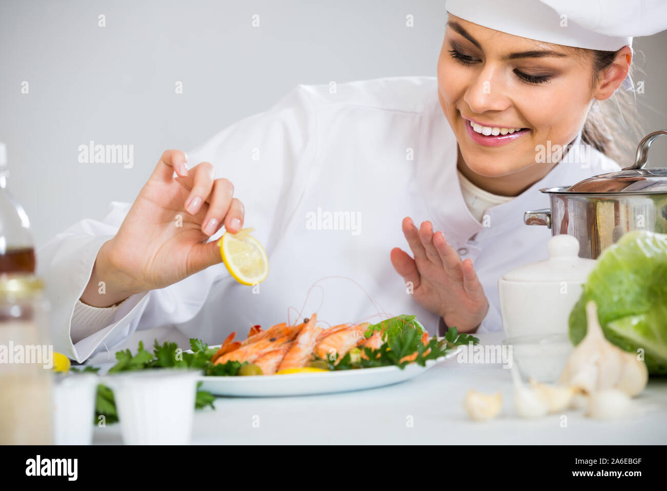 Professional cook decorating prepared shrimps on dish in restaurant ...