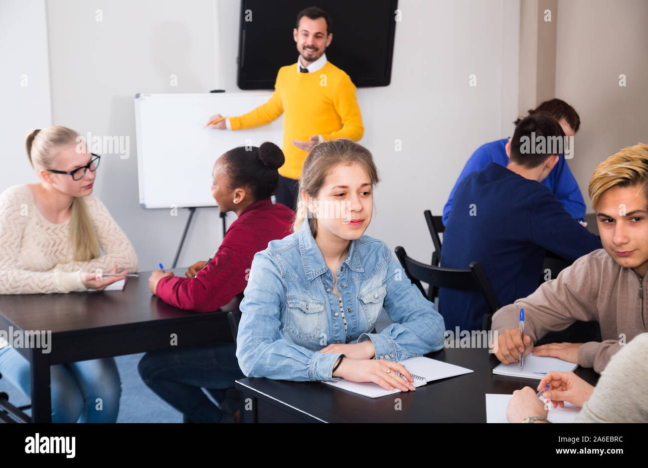 Young female and male students are working in large groups in school ...