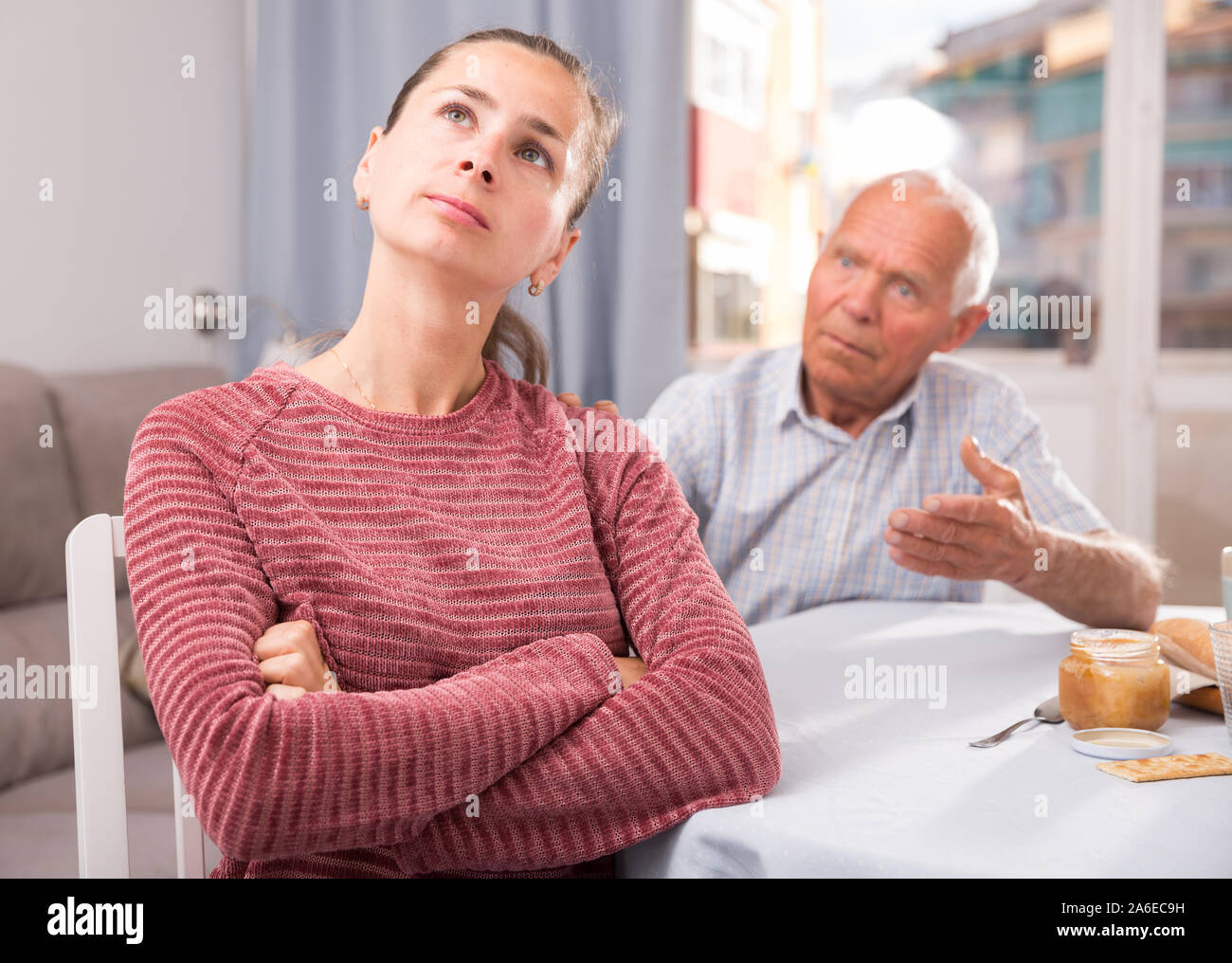 Portrait of upset young woman sitting after quarrel with father at home ...