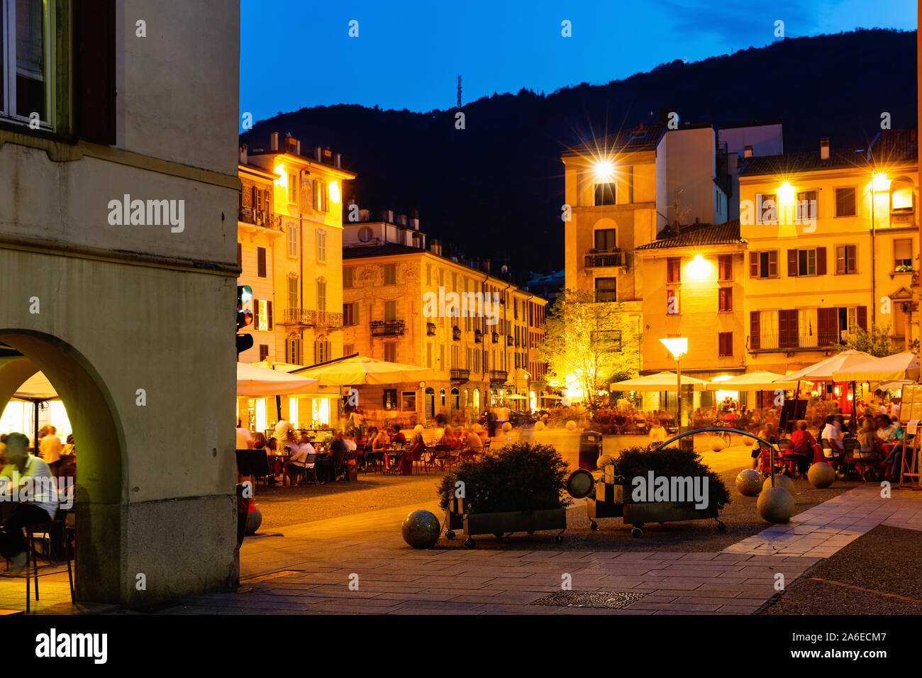 The streets and buildings of Como city in evening near mountains in ...
