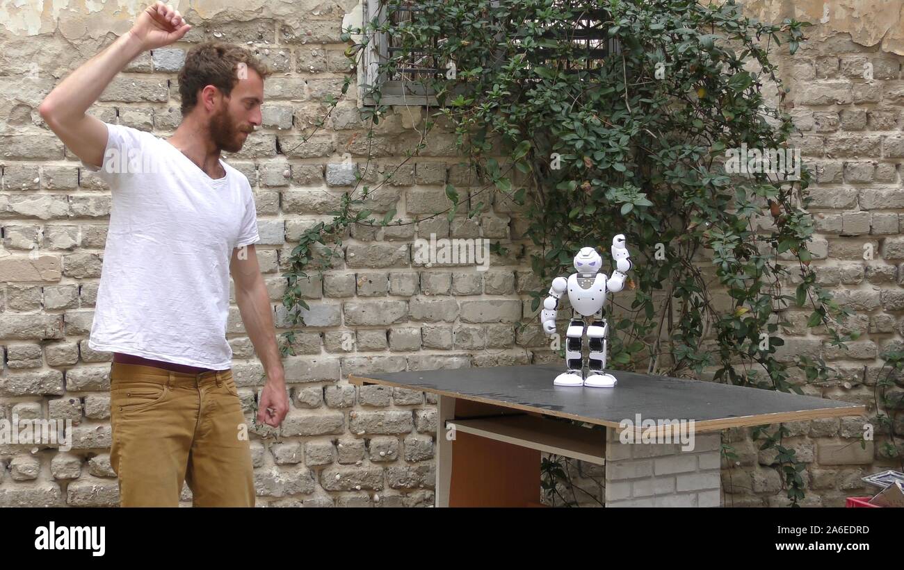 A humanoid robot teaches a young man to dance. The man sees the robot ...