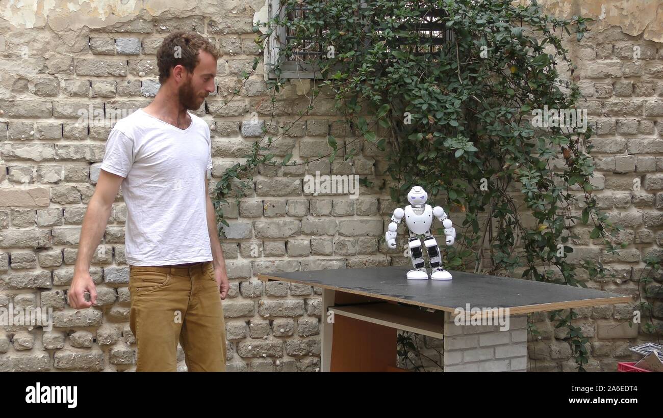 A humanoid robot teaches a young man to dance. The man sees the robot ...