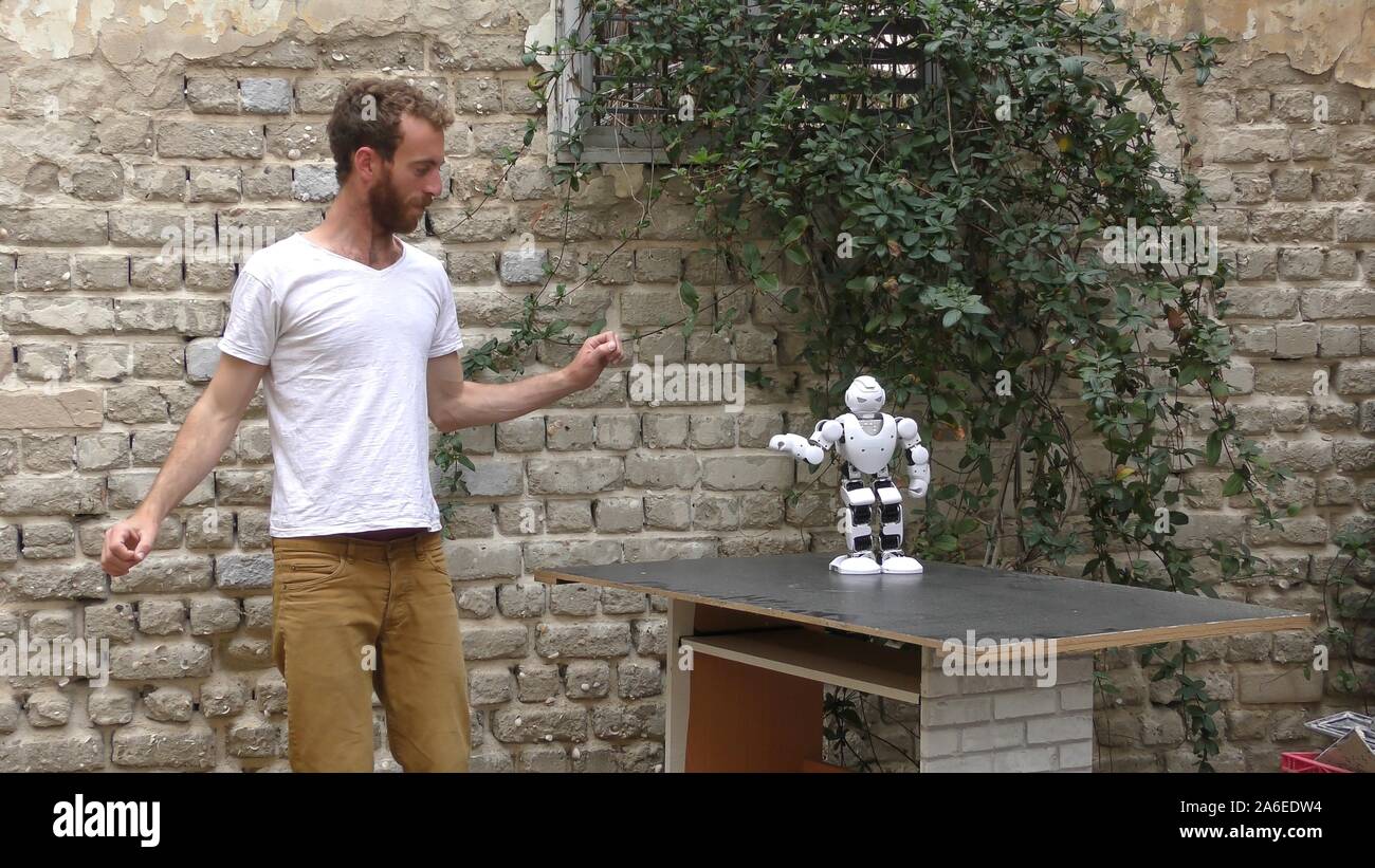 A humanoid robot teaches a young man to dance. The man sees the robot ...
