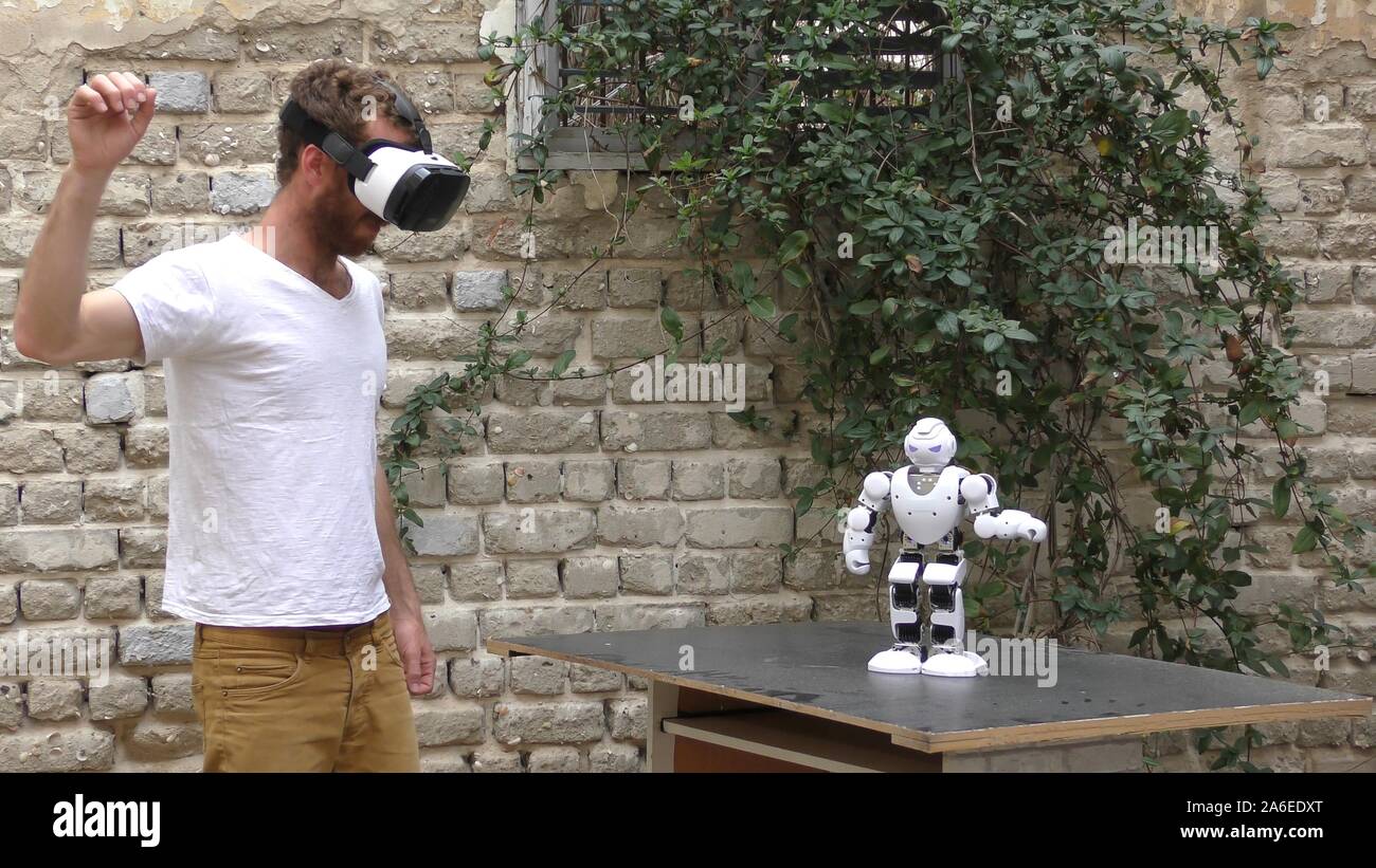 A humanoid robot teaches a young man to dance. The man sees the robot ...