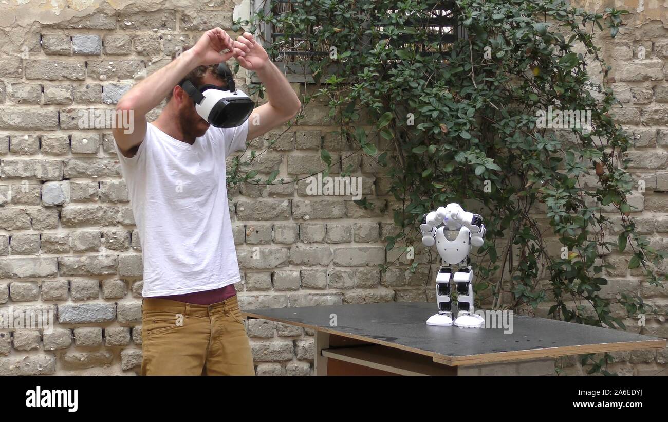 A humanoid robot teaches a young man to dance. The man sees the robot ...