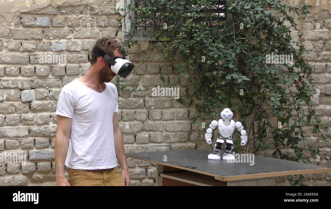 A humanoid robot teaches a young man to dance. The man sees the robot ...