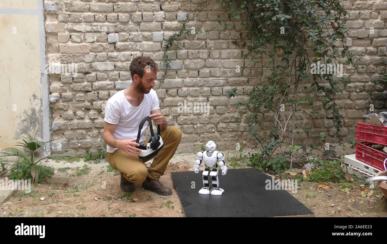A humanoid robot and a young man exercise push ups because they want to ...