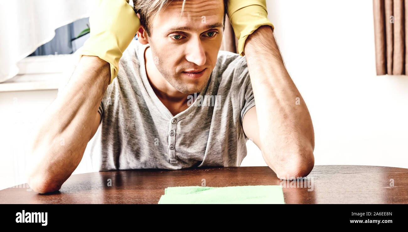 Unhappy man with gloves while cleaning table. Houseworking routine ...