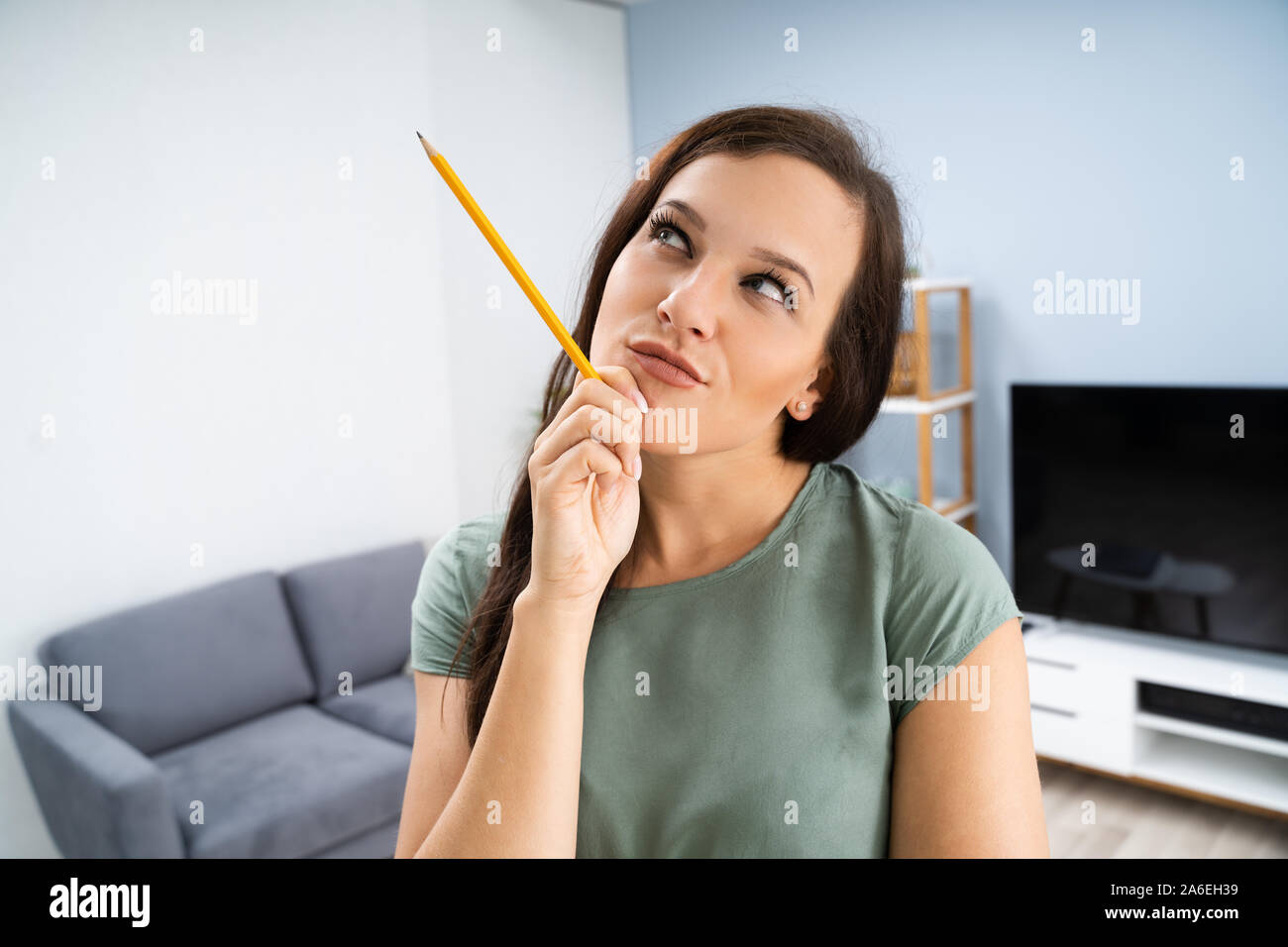 Portrait Of Thoughtful Young Woman In Living Room Stock Photo - Alamy