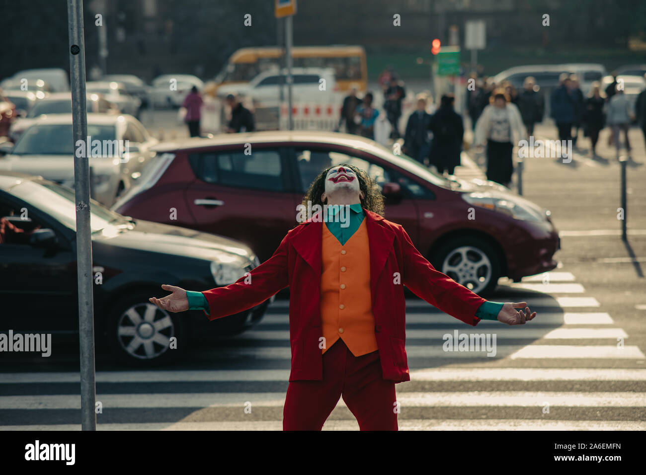 Cosplayer portrays a crazy clown against background of a city street ...
